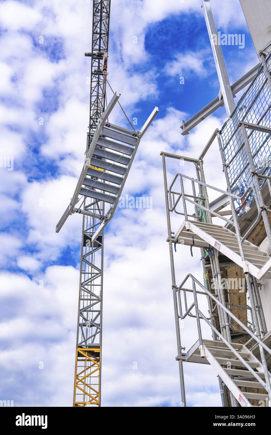 Crane lifts stair structure next to scaffolding in cloudy sky, stair ...