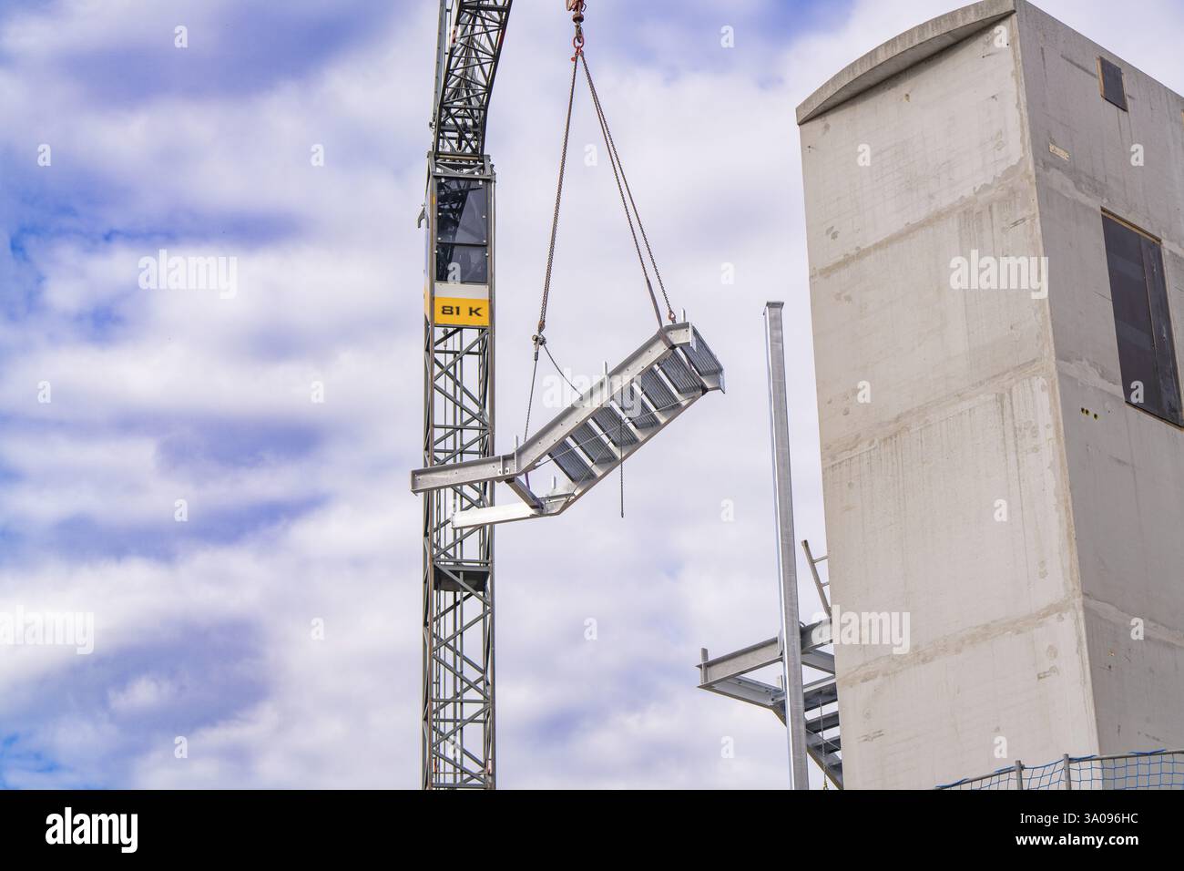 Crane moves a large steel girder upwards on a construction site ...