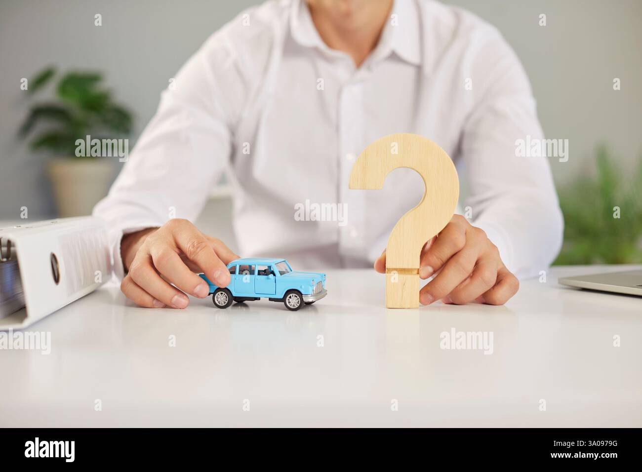 Car insurance agent with a small automobile model and a question mark ...