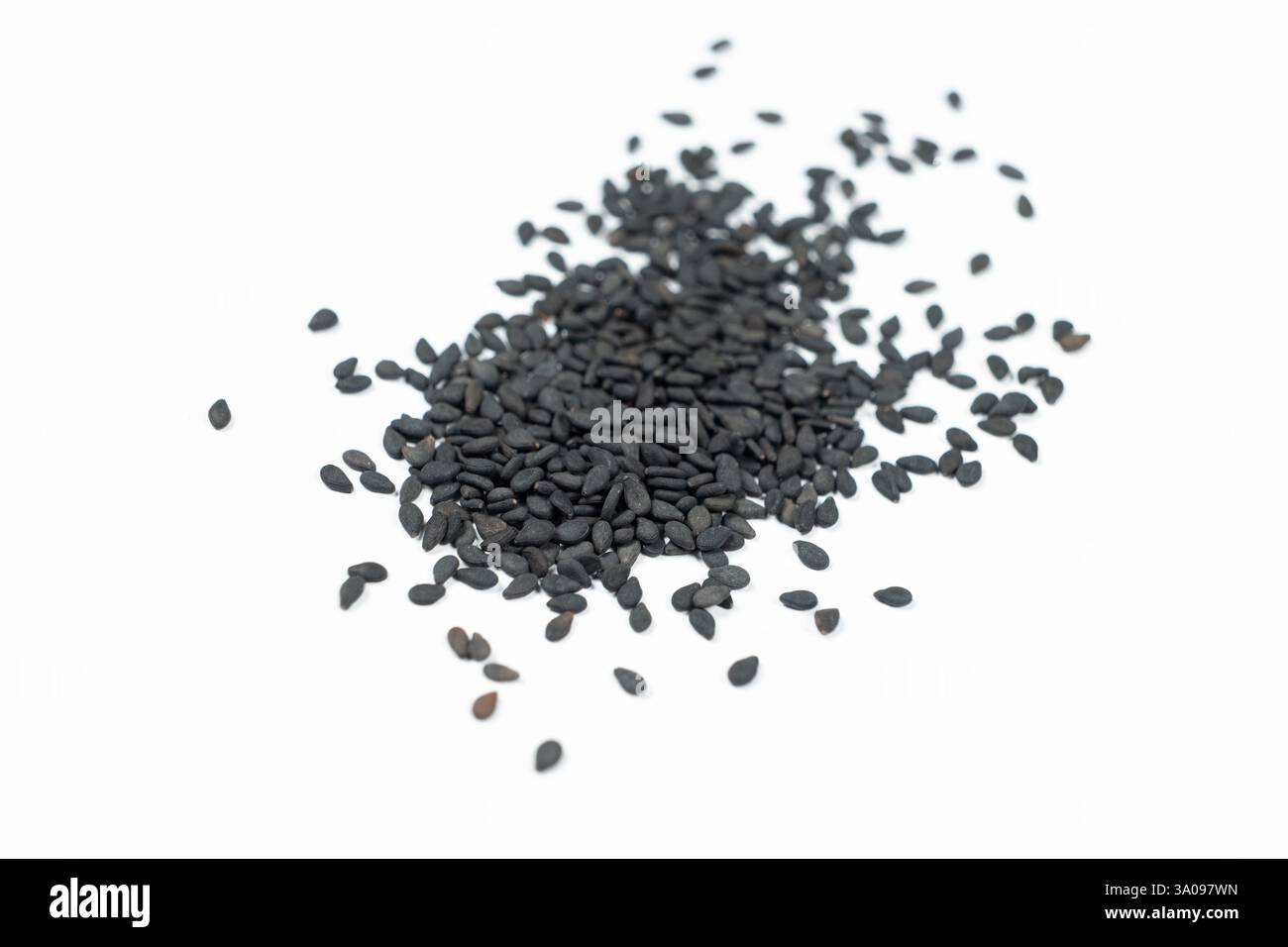 Black sesame seeds scattered on a white background macro side view ...