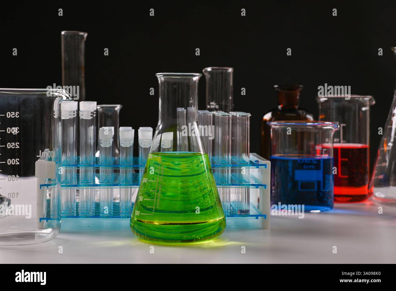 Glassware containing colorful chemical liquid on laboratory table with ...