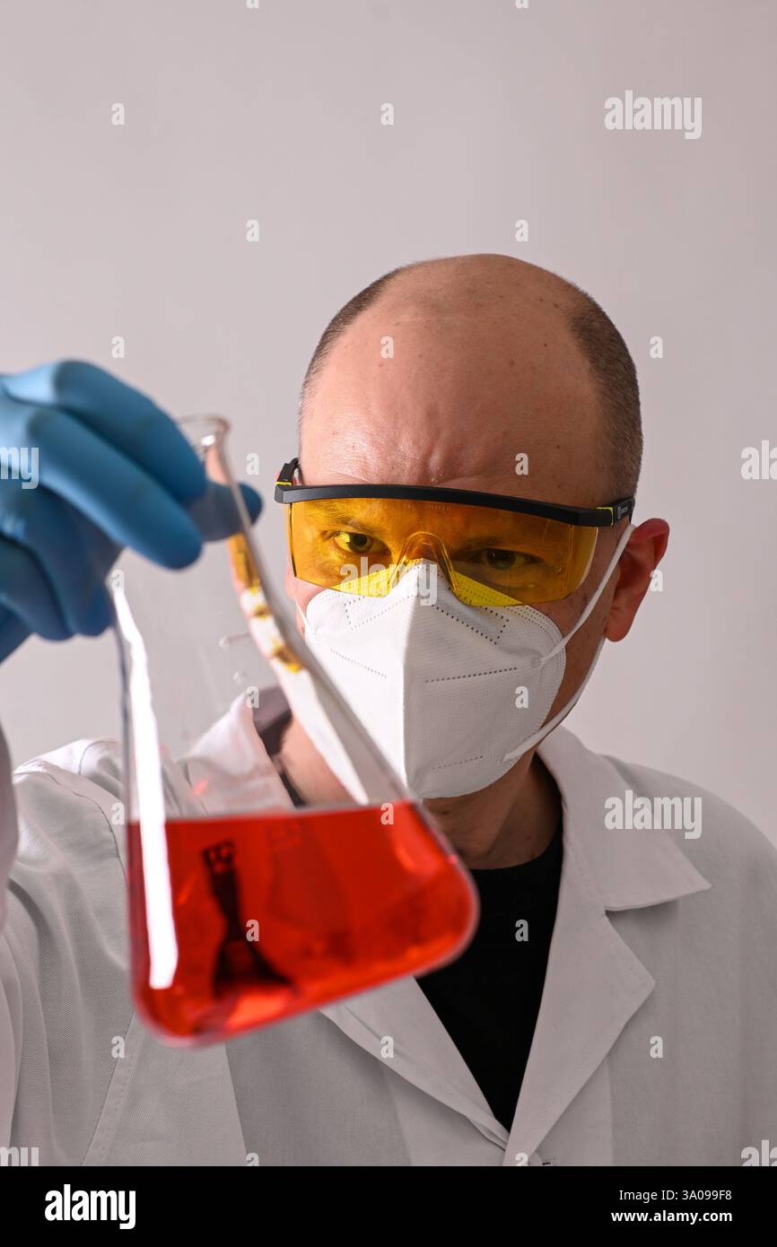 Scientist examining red liquid in erlenmeyer flask, conducting ...