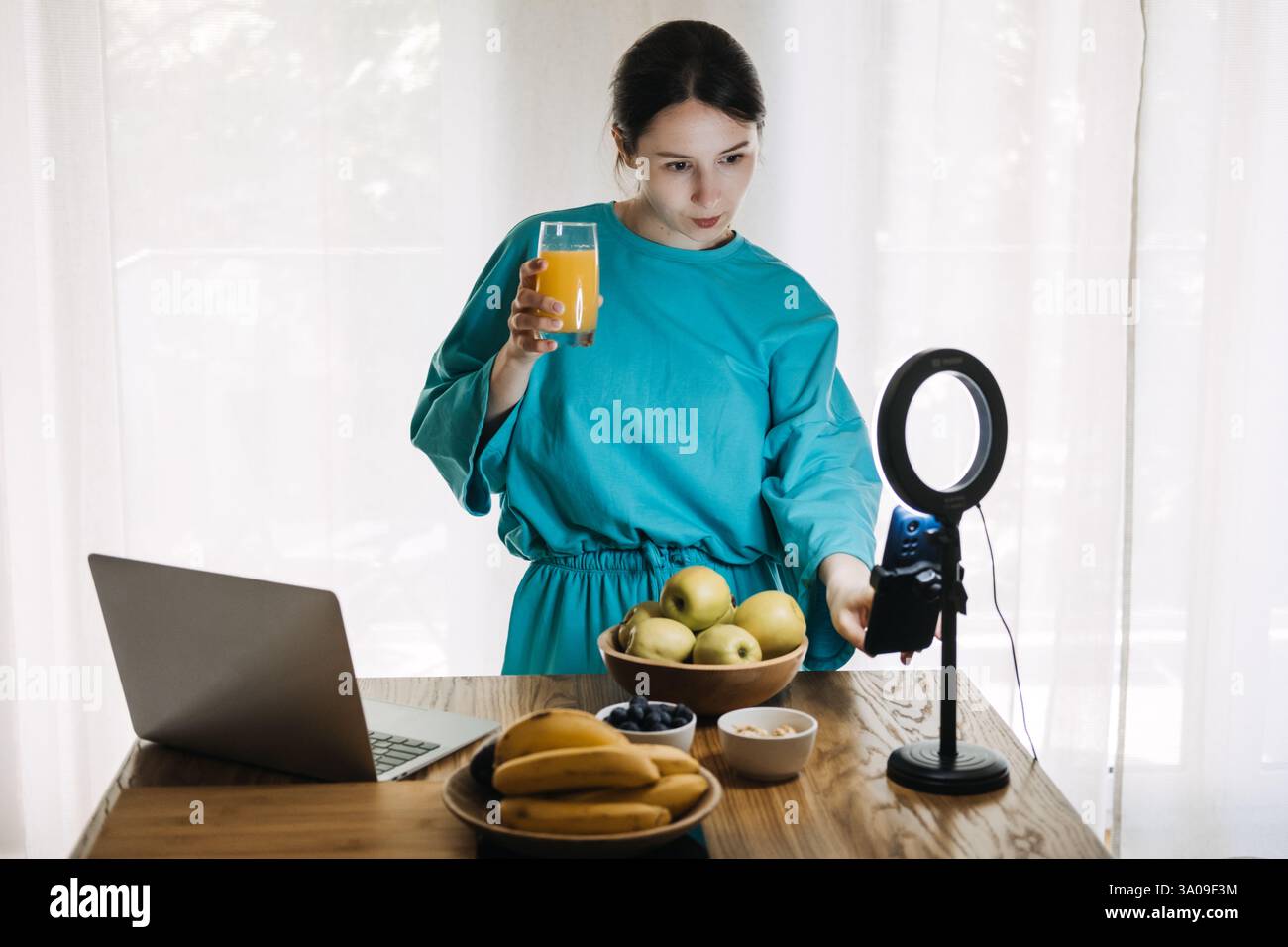 Woman filming with a ring light and fresh produce. Vlogging at home ...