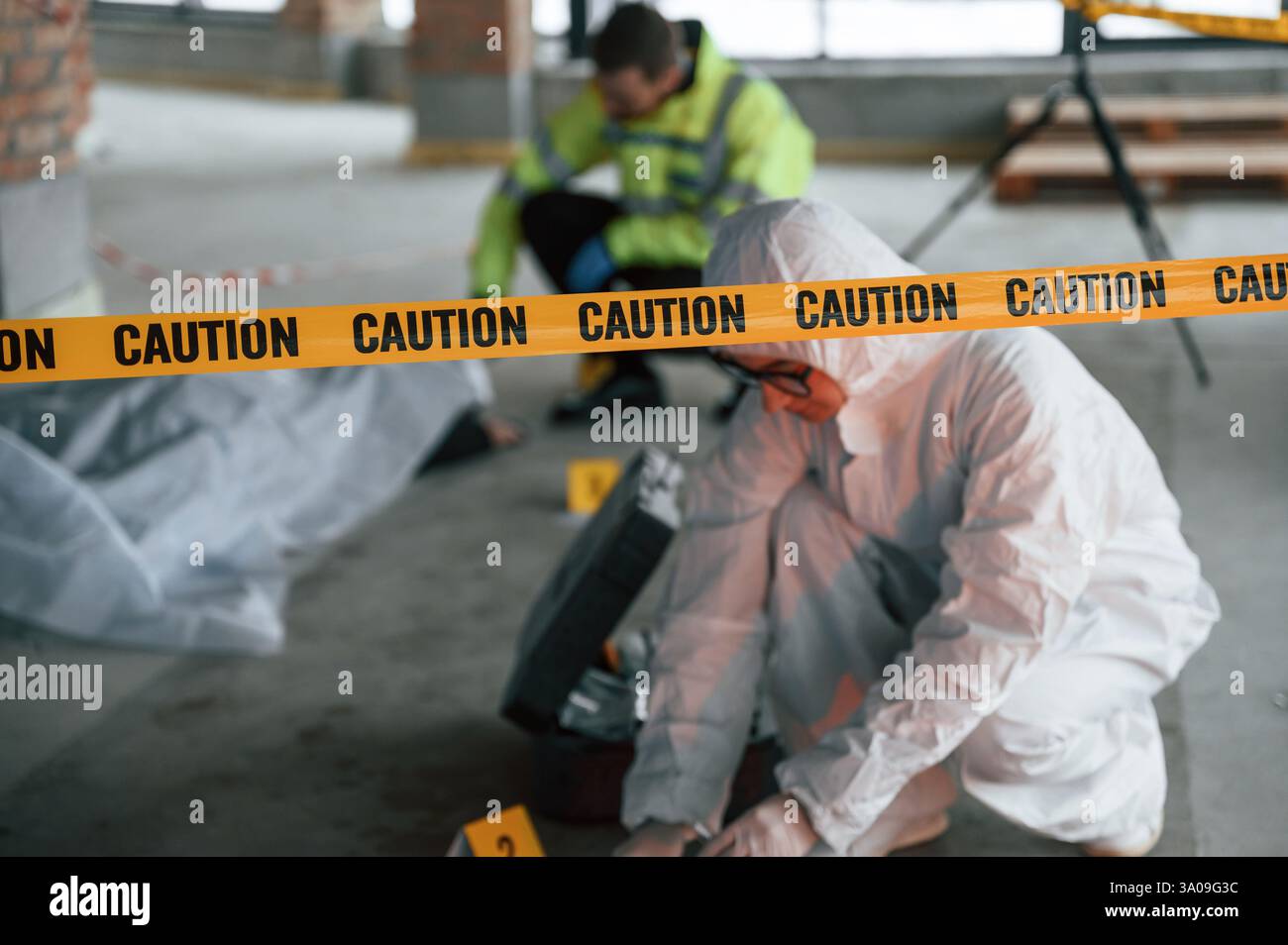 Caution police tape. Detectives are collecting evidence in a crime scene near dead body Stock ...