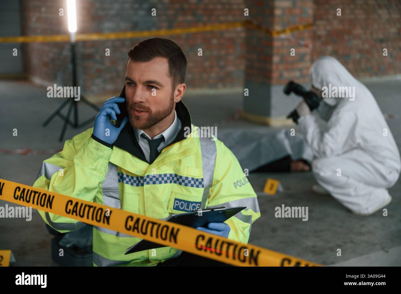 Man is talking by phone. Detectives are collecting evidence in a crime ...