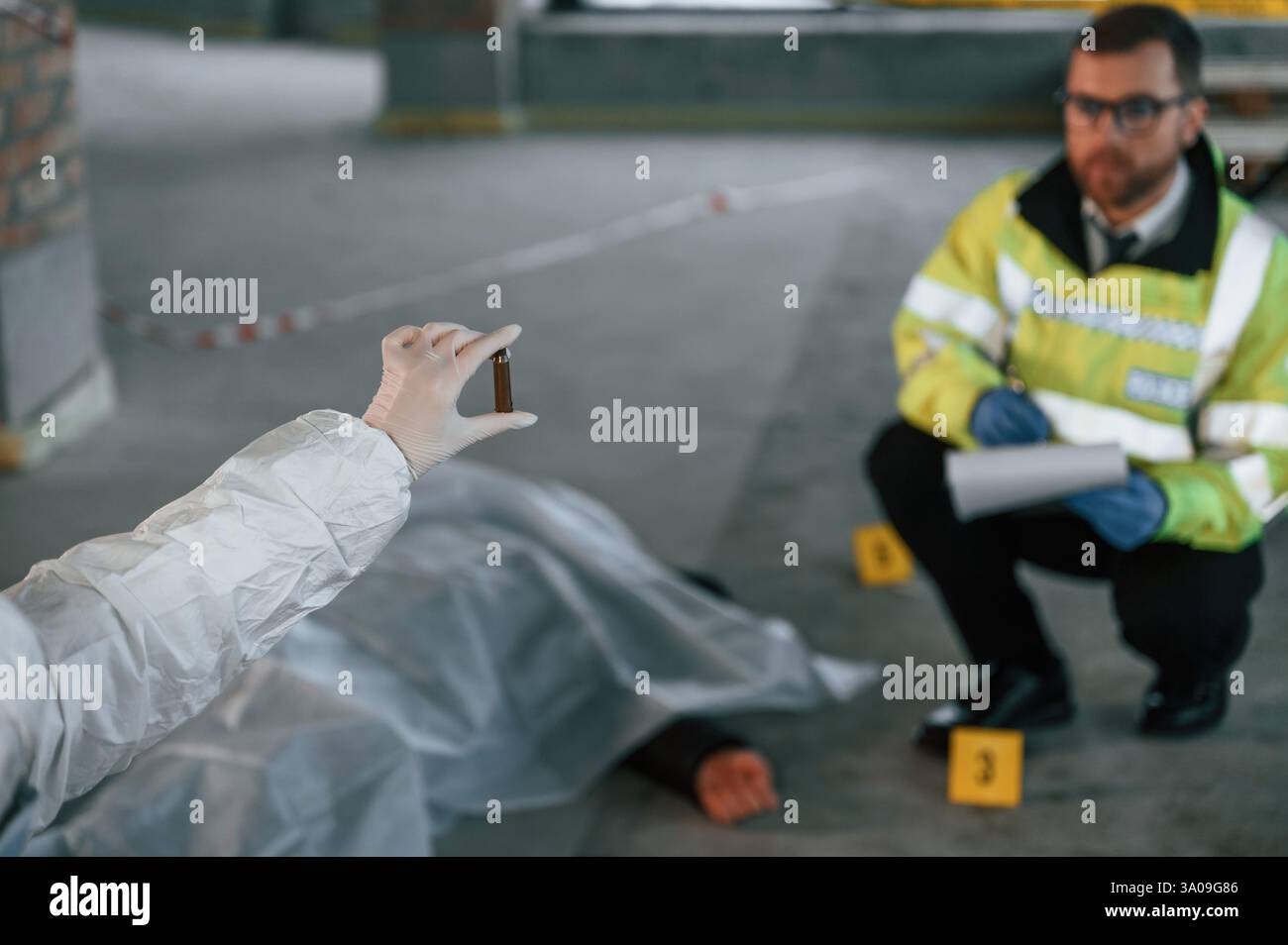 A woman is holding a shell casing. Detectives are collecting evidence ...