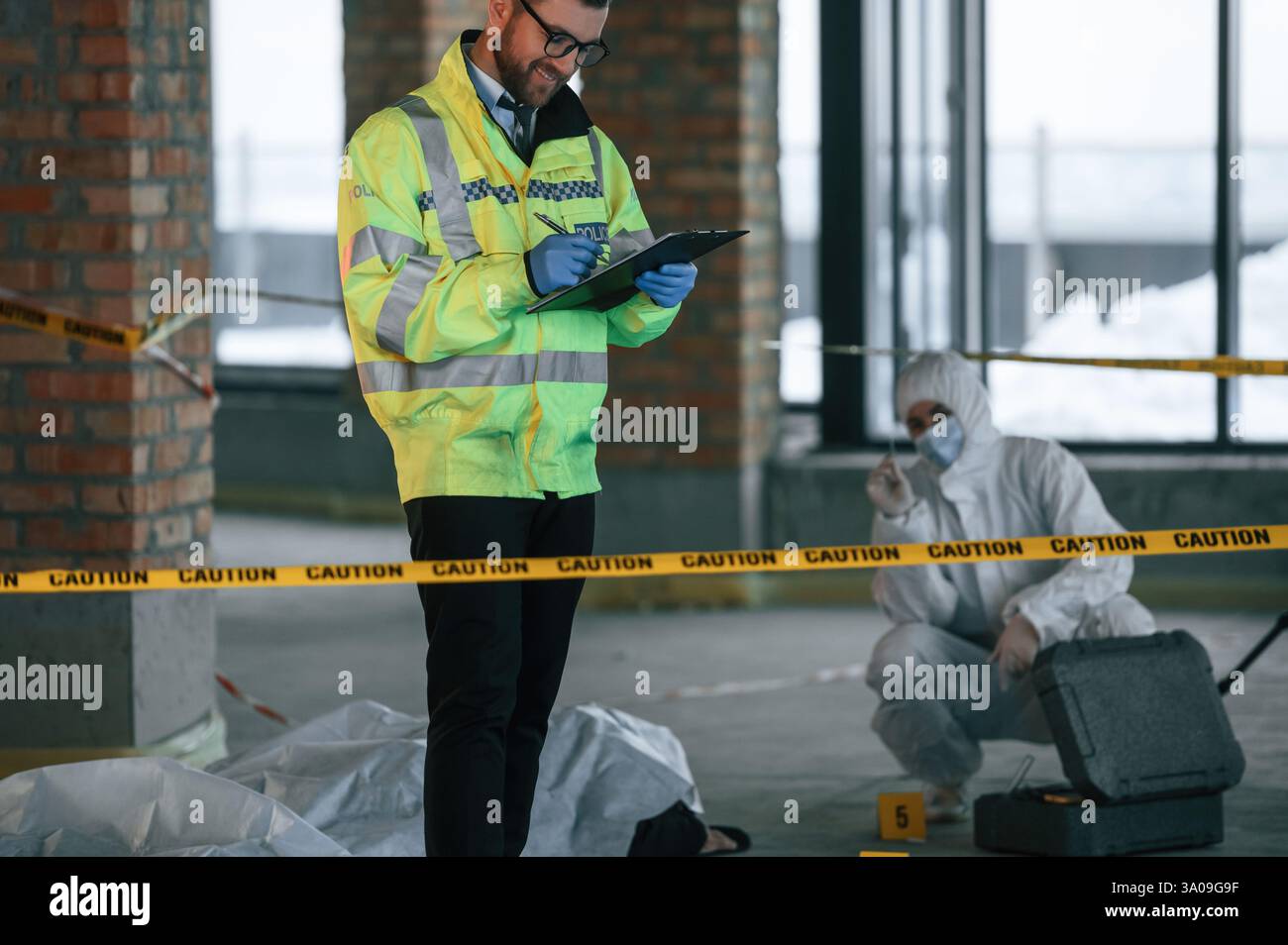 Man is standing and smiling. Detectives are collecting evidence in a ...
