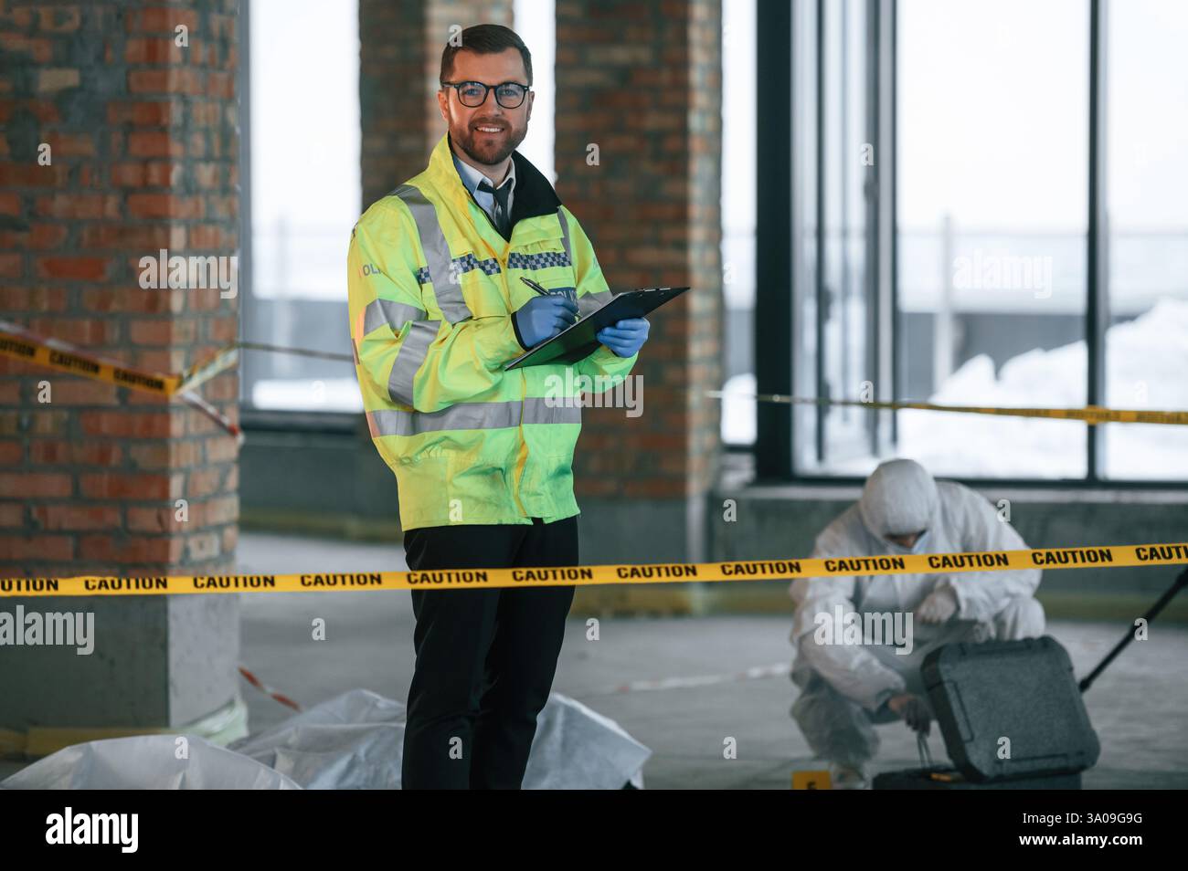 Man is standing and smiling. Detectives are collecting evidence in a ...
