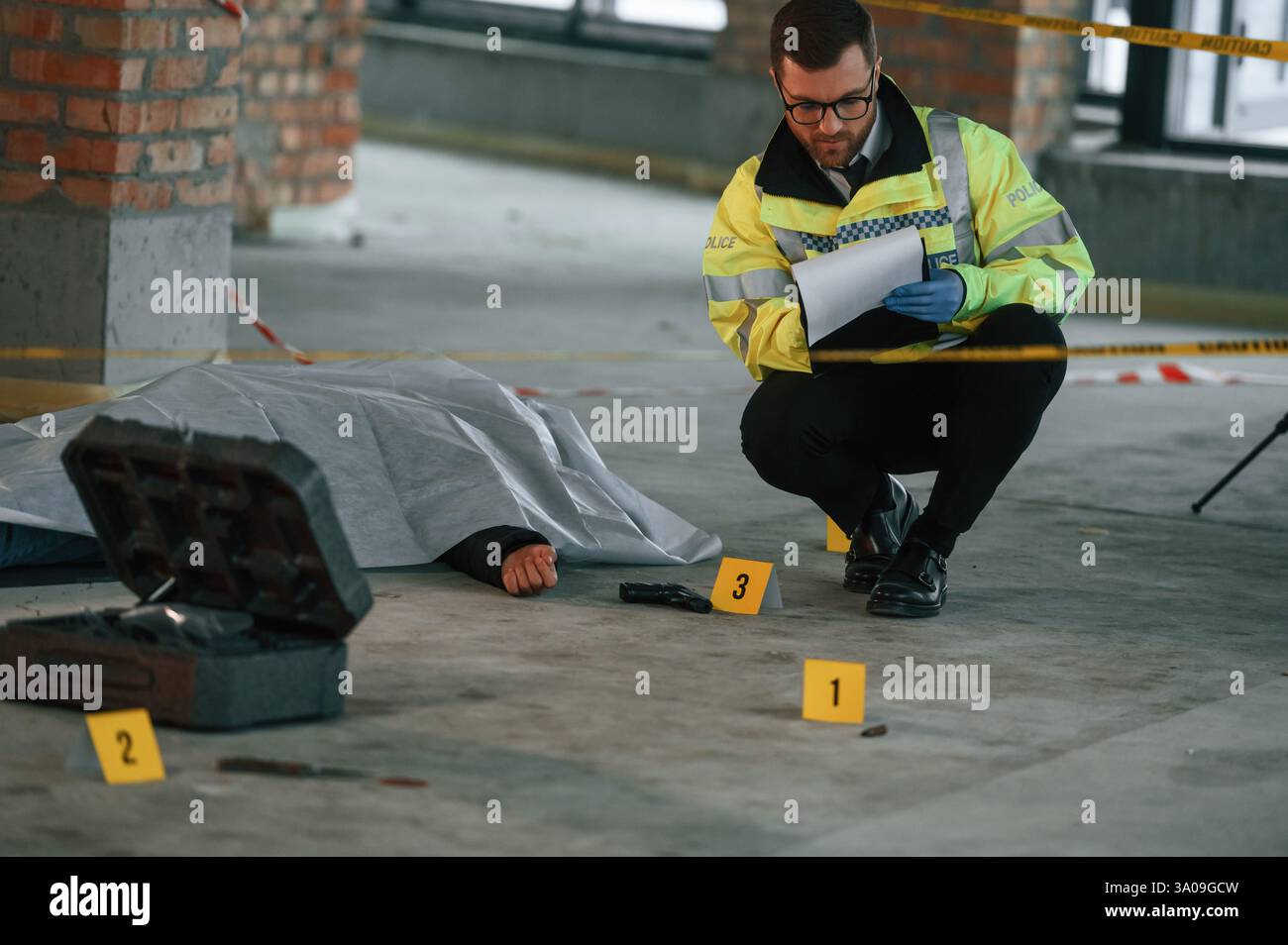 Notepad with information. Male detective is collecting evidence in a crime scene near dead body ...