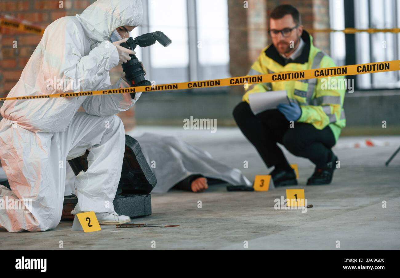 Woman is making photos by camera. Detectives are collecting evidence in ...