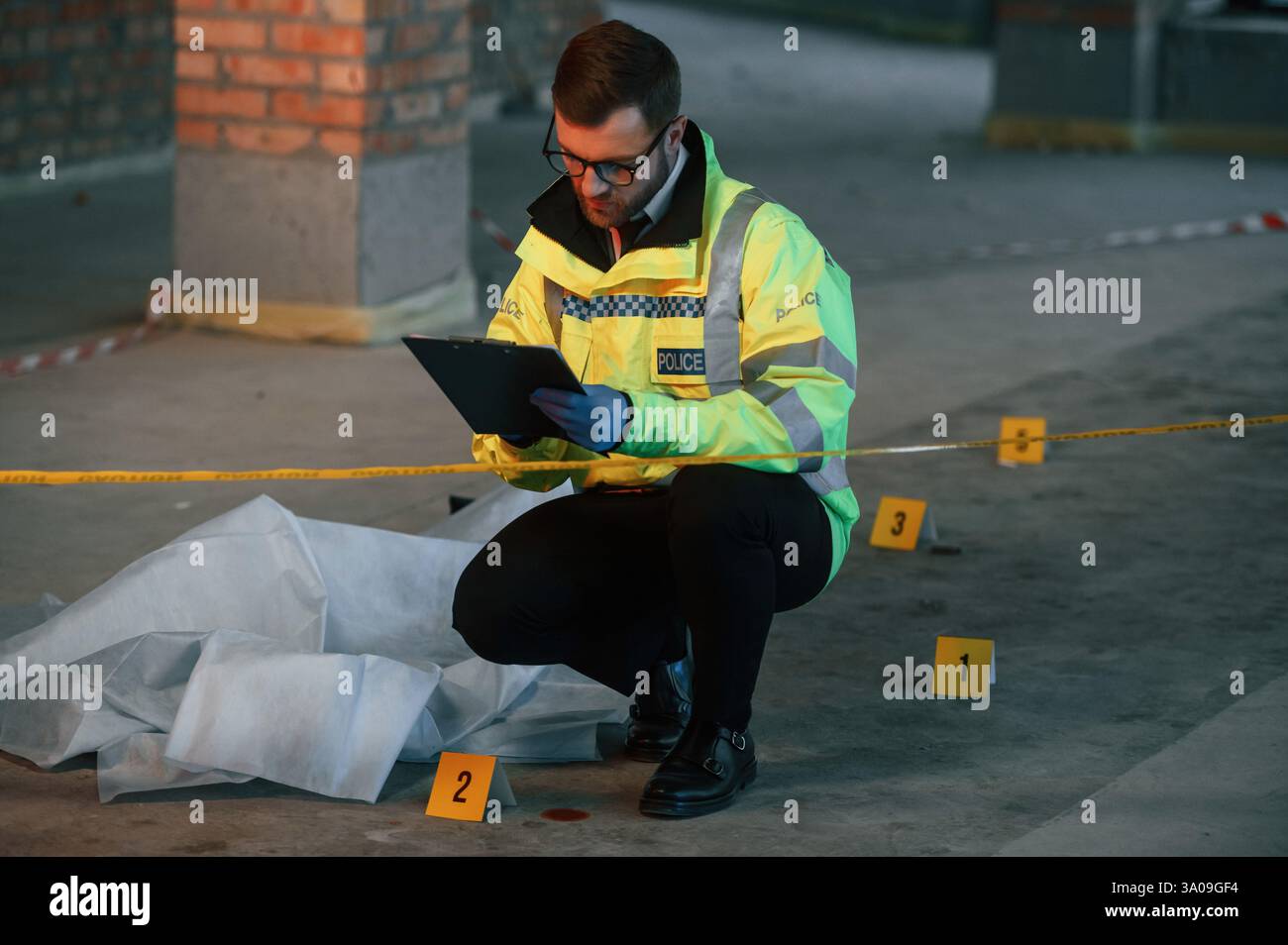 Male detective is collecting evidence in a crime scene near dead body ...