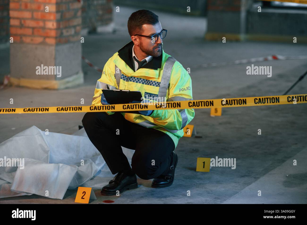 Male detective is collecting evidence in a crime scene near dead body ...