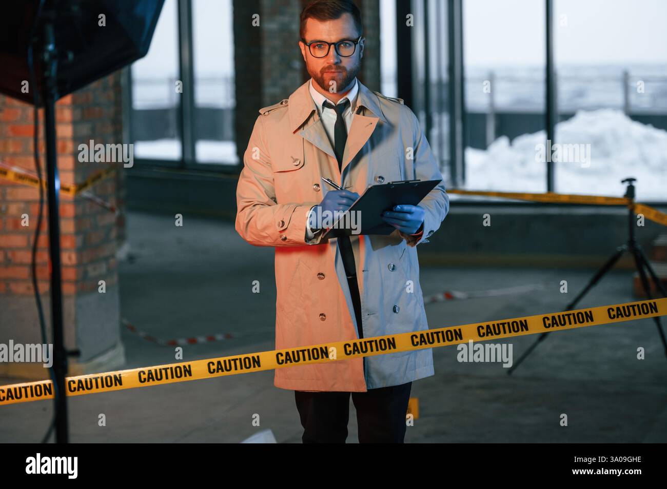 Male detective in coat is collecting evidence in a crime scene on the ...
