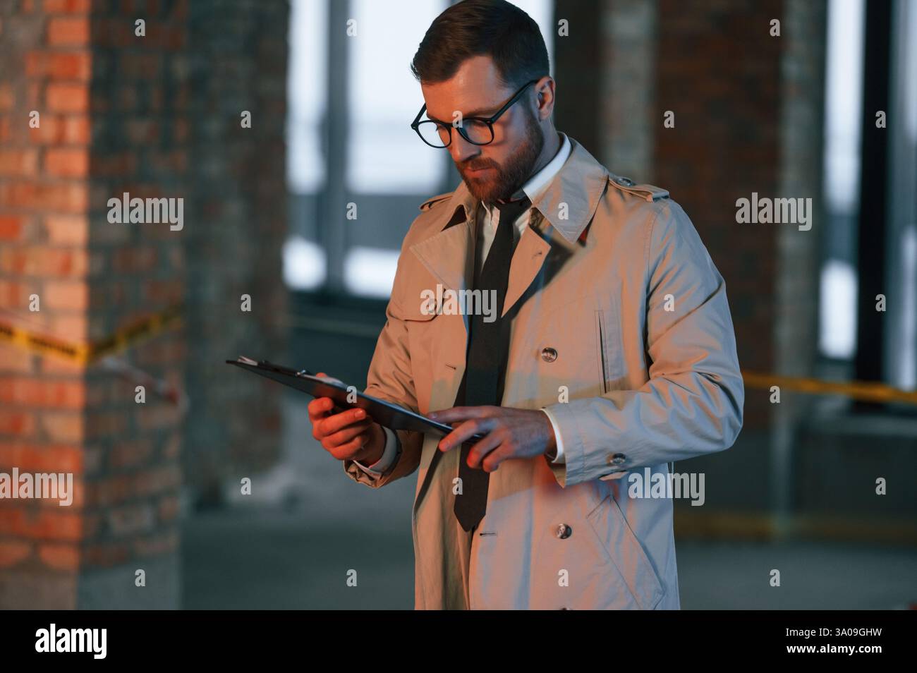 Male detective in coat is collecting evidence in a crime scene on the ...