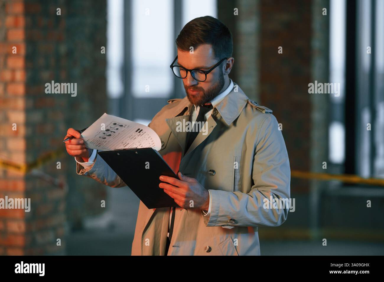Male detective in coat is collecting evidence in a crime scene on the ...
