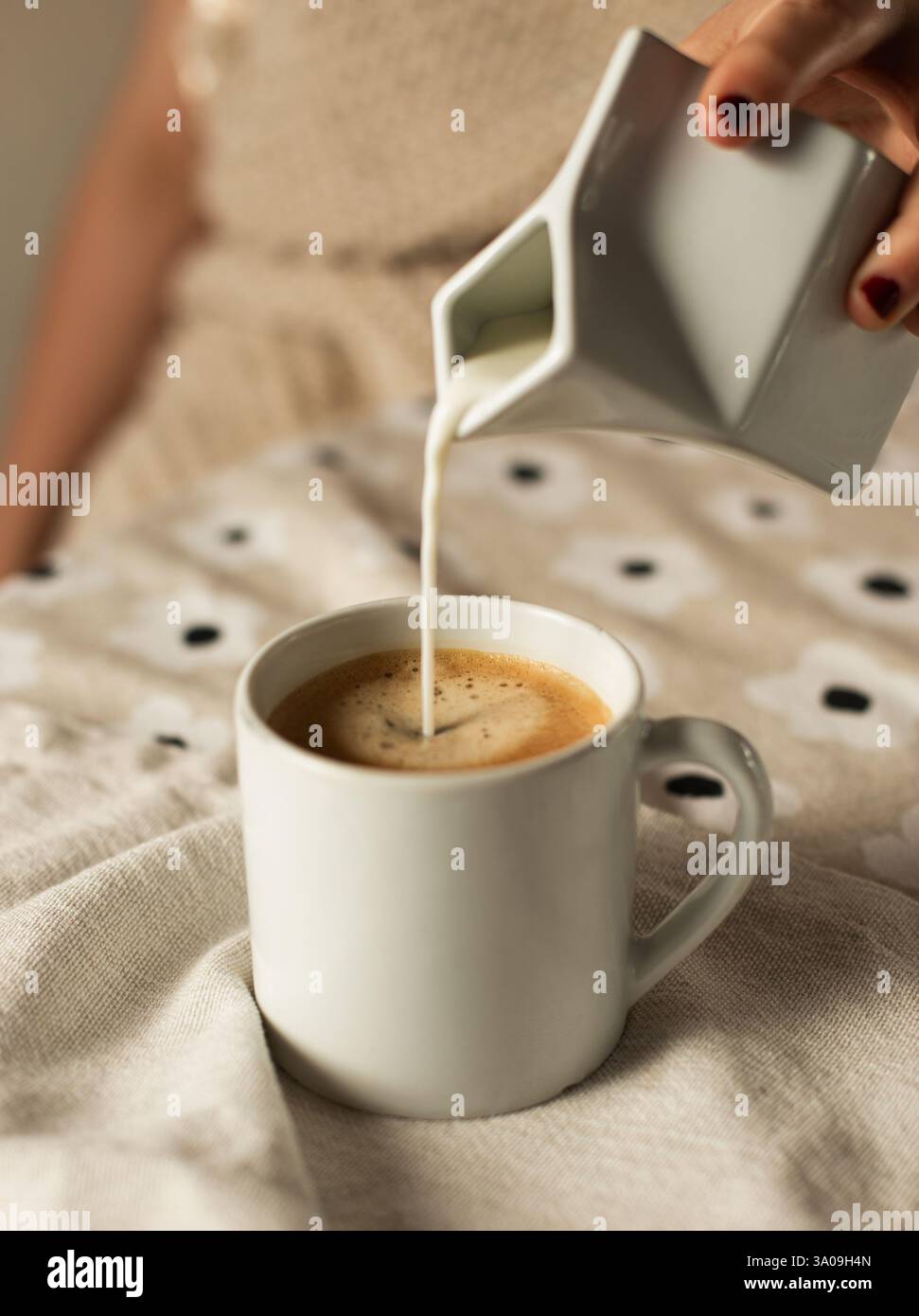 Woman pouring milk into mug of coffee Stock Photo - Alamy