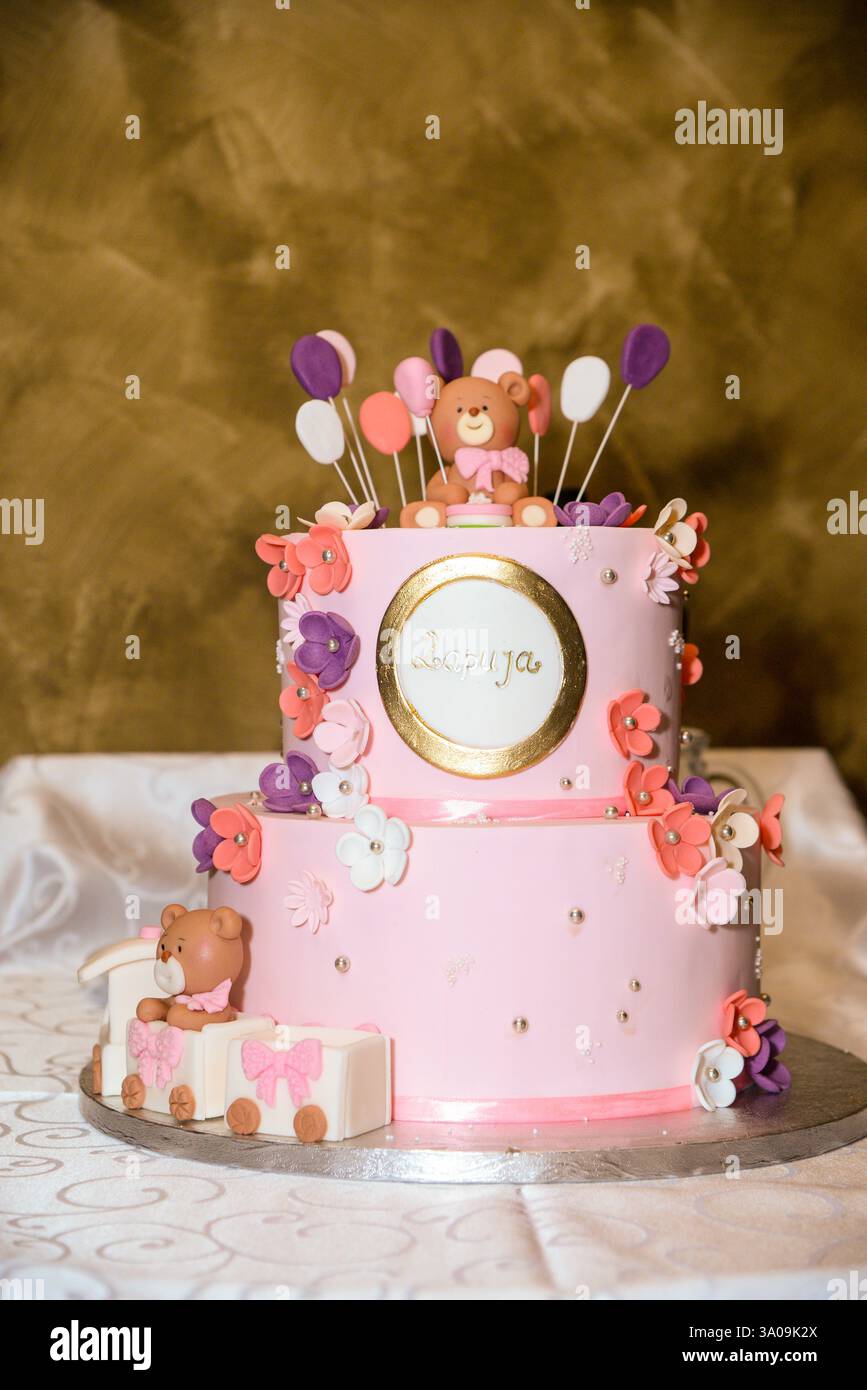 A two-tiered pink cake decorated with pink, white and purple flowers ...