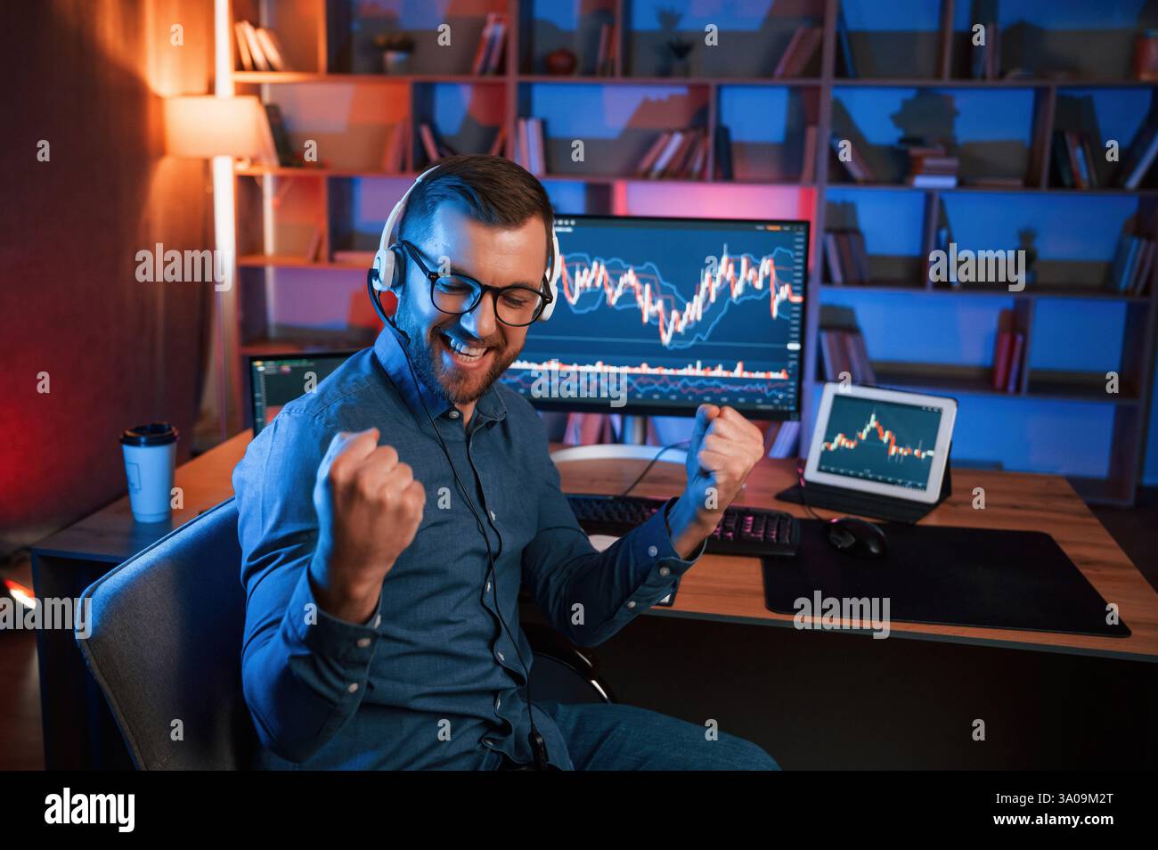 Happy stock trader is working by pc indoors and celebrating success ...
