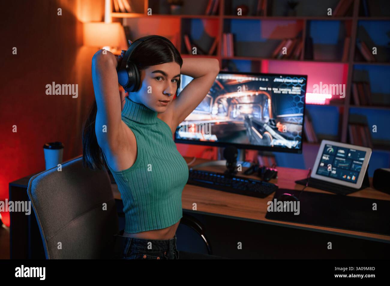 Young pretty female gamer is playing shooter. Neon lighting Stock Photo ...