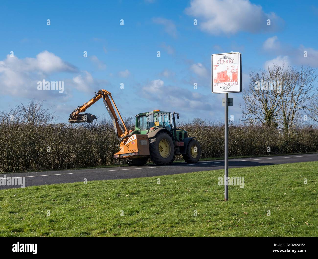 Trimming hedge tops with motorised trimmer on back of John Deere ...
