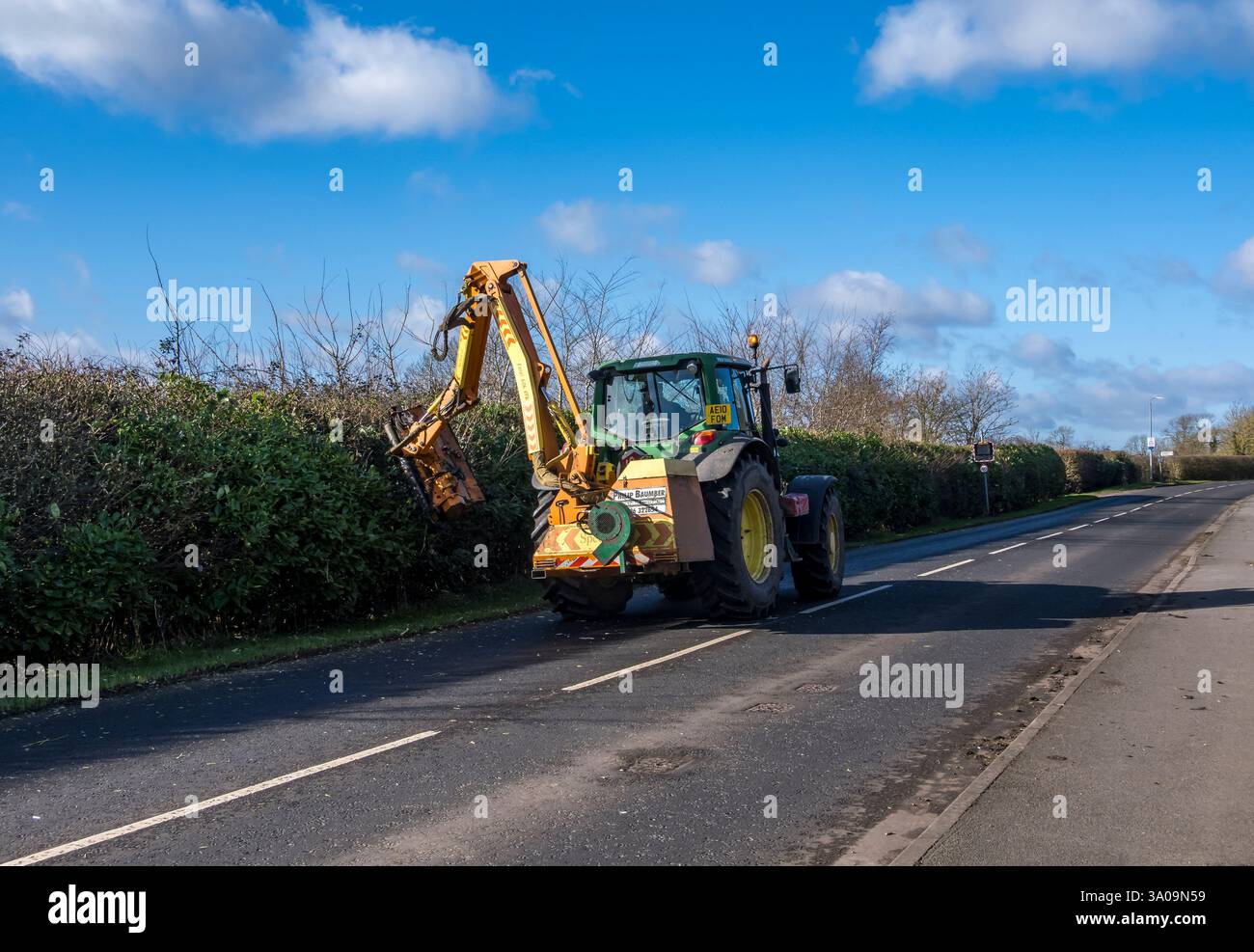 Trimming side of hedge with motorised trimmer on back of John Deere ...