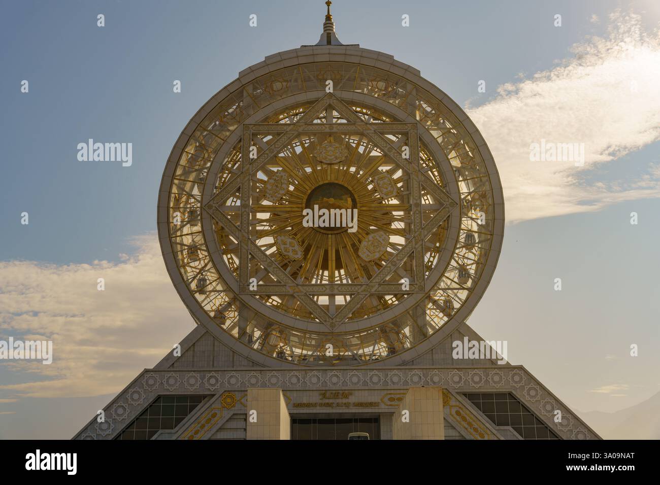 A large golden wheel with a sun in the center Stock Photo - Alamy