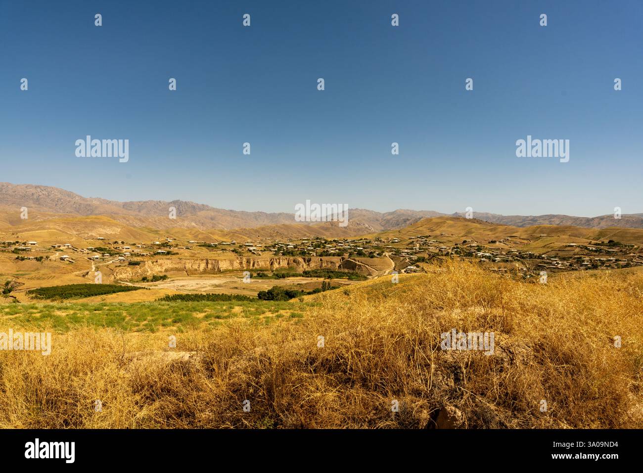 A dry, barren landscape with a few houses in the distance Stock Photo ...