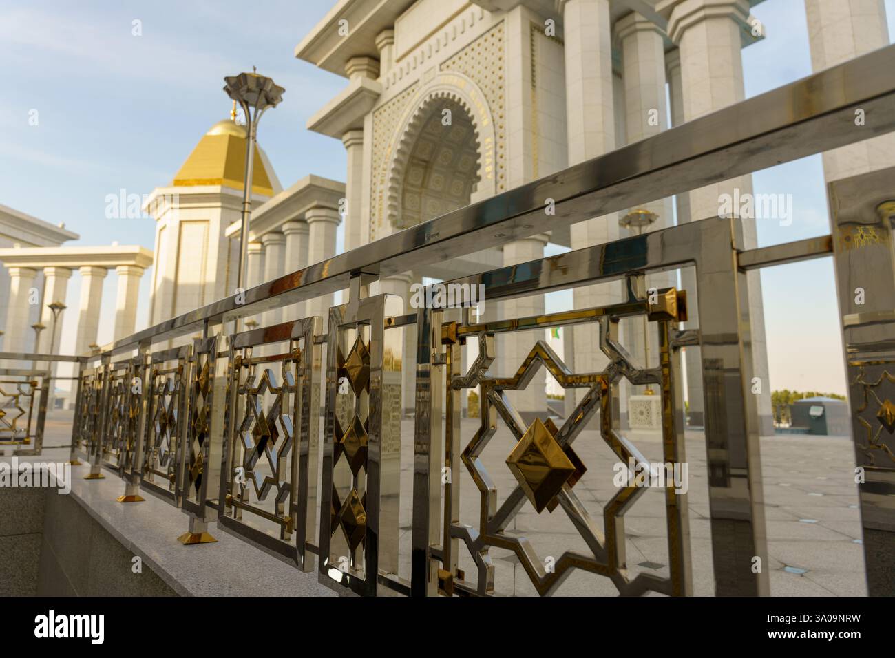 A metal fence with gold accents sits in front of a large building Stock ...