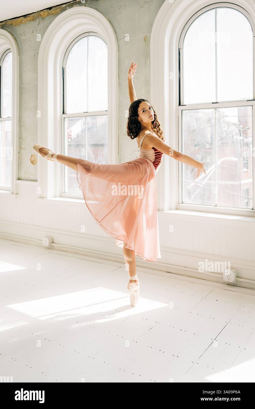Ballerina performs an arabesque en pointe in a sunlit studio Stock ...