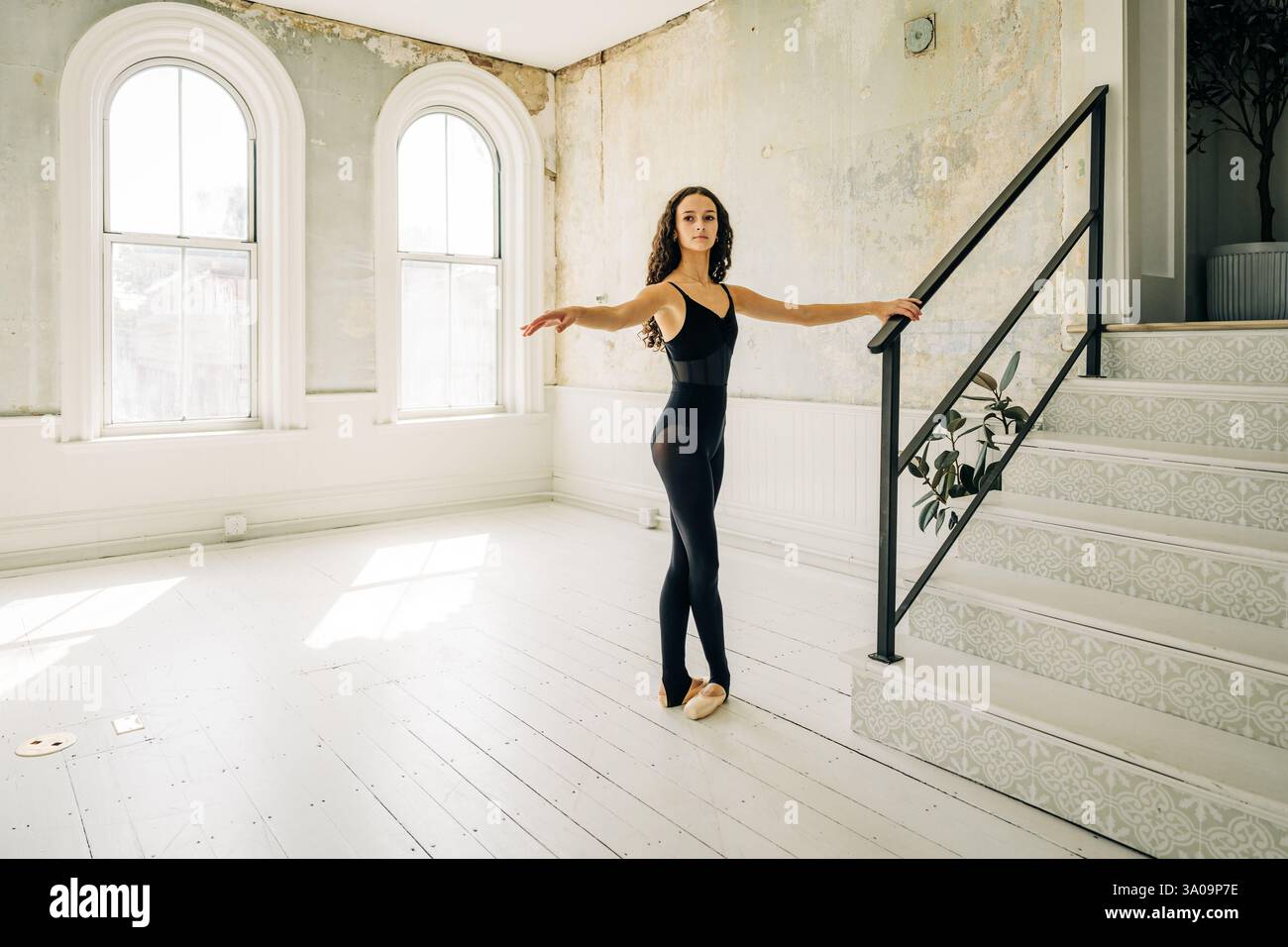 Ballet dancer practicing at a railing in a rustic, sunlit studio Stock ...