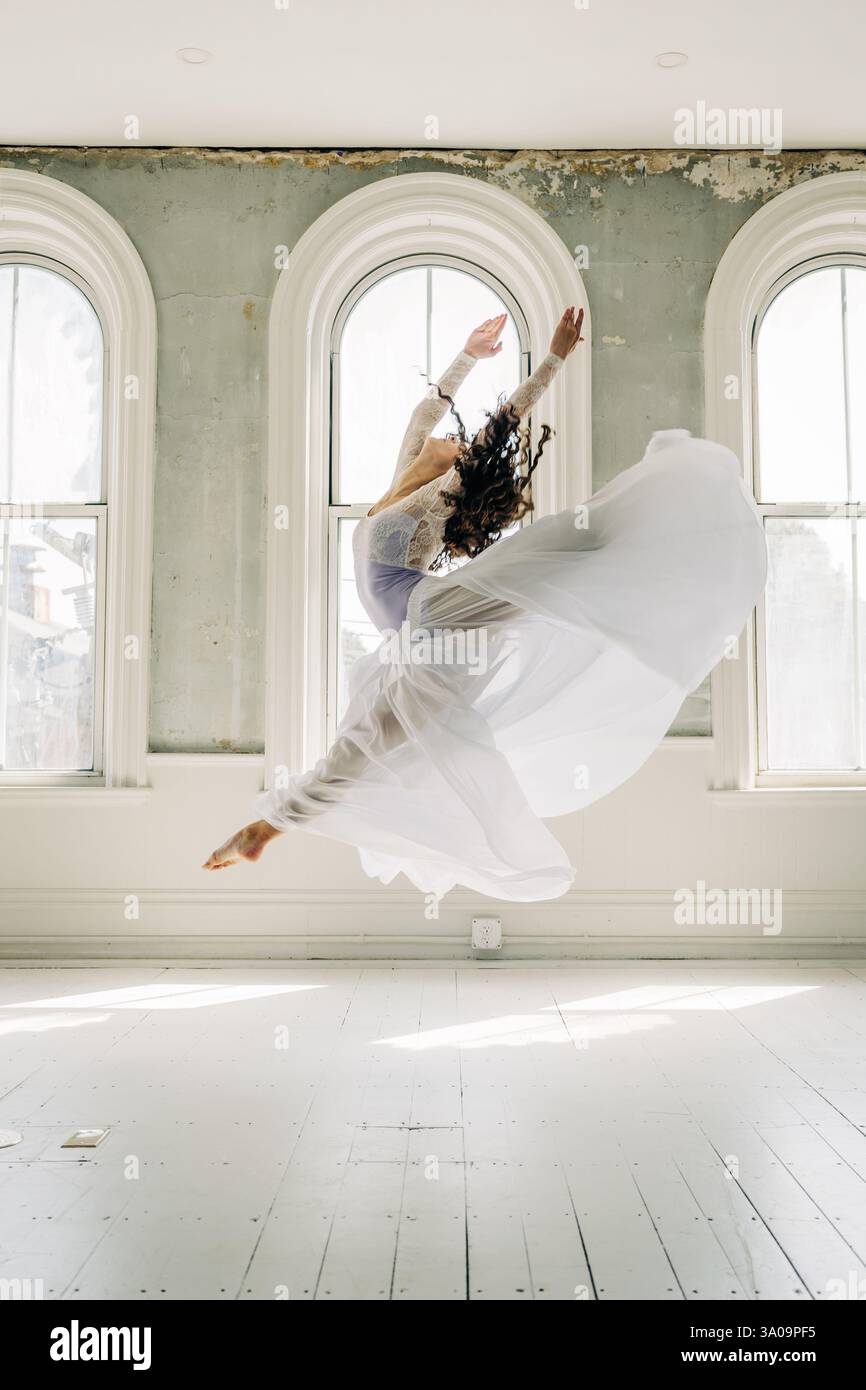 Ballerina soars mid-leap, flowing dress enhancing movement Stock Photo ...