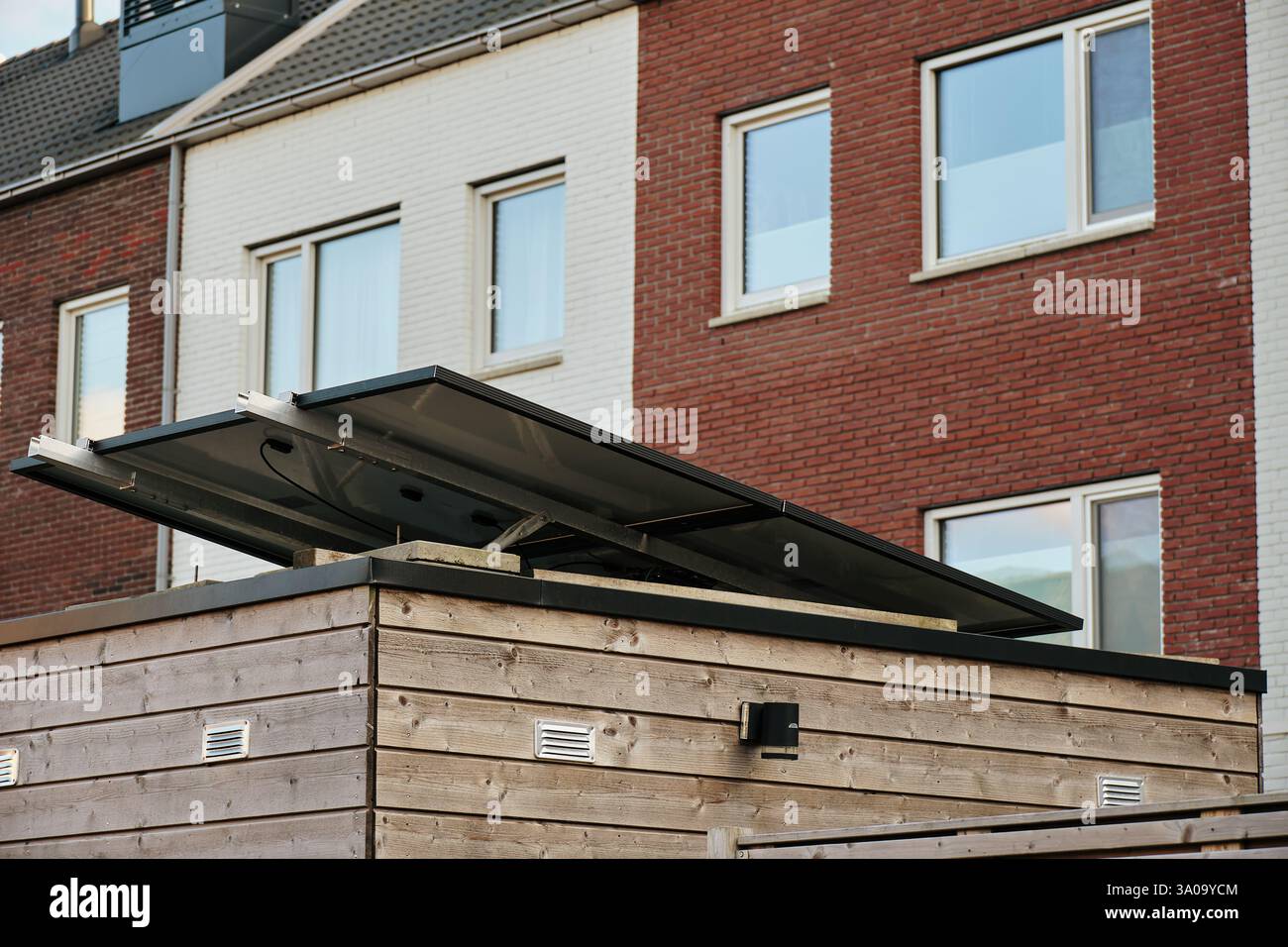 A solar panel mounted on a wooden shed, angled to capture sunlight for ...