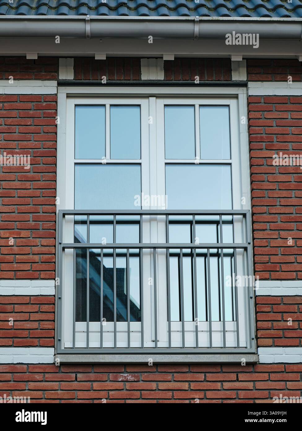A modern French balcony with a white-framed window and metal railing on ...