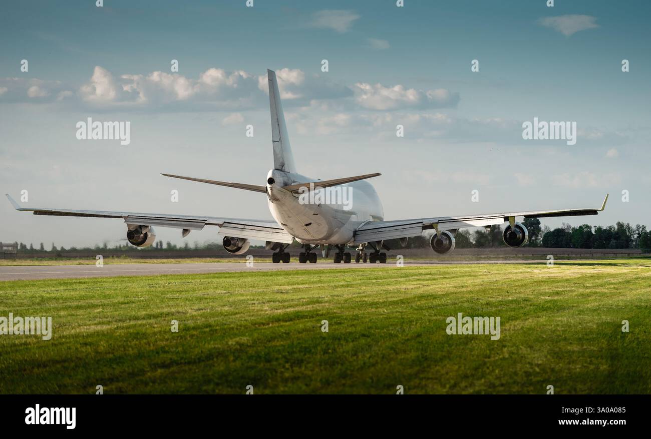 White cargo airplane on taxiway rolling away from camera. Rear view of ...