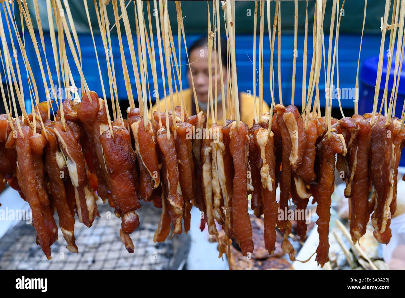 Strips of meat hang to dry in the sun ready to be grilled at a Bangkok ...