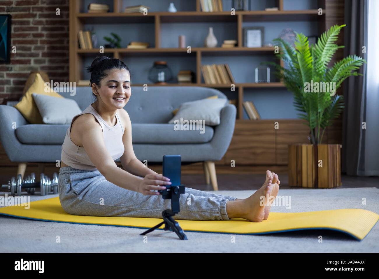 A young woman recording her workout session on her phone, sitting on a ...