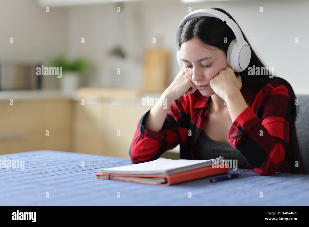 Asian student studying reading notes listening tutorial in the kitchen ...