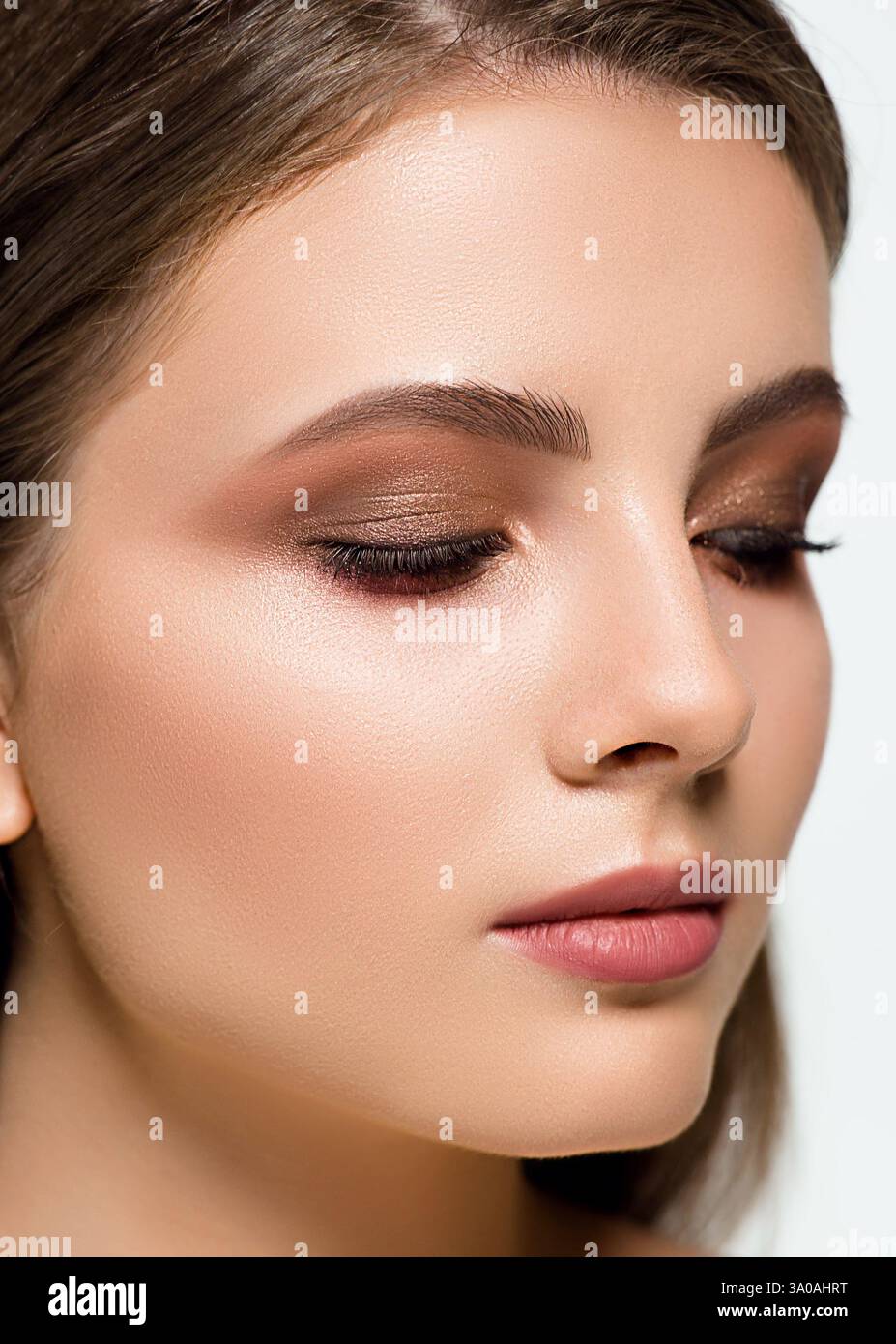 A young woman displays a natural makeup look, highlighting her radiant ...