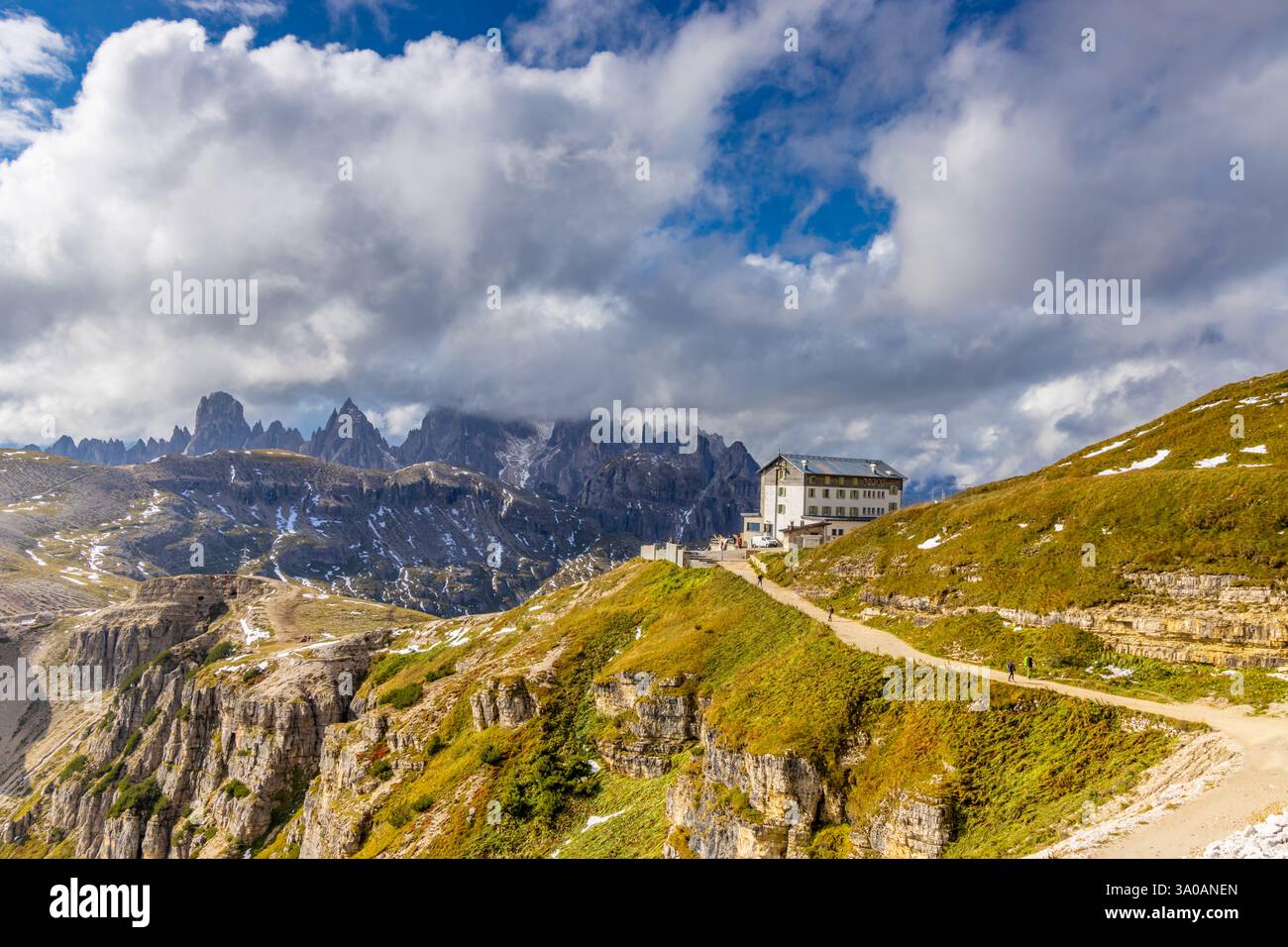 A mountain refuge at the base of rugged rock formations under a clear ...