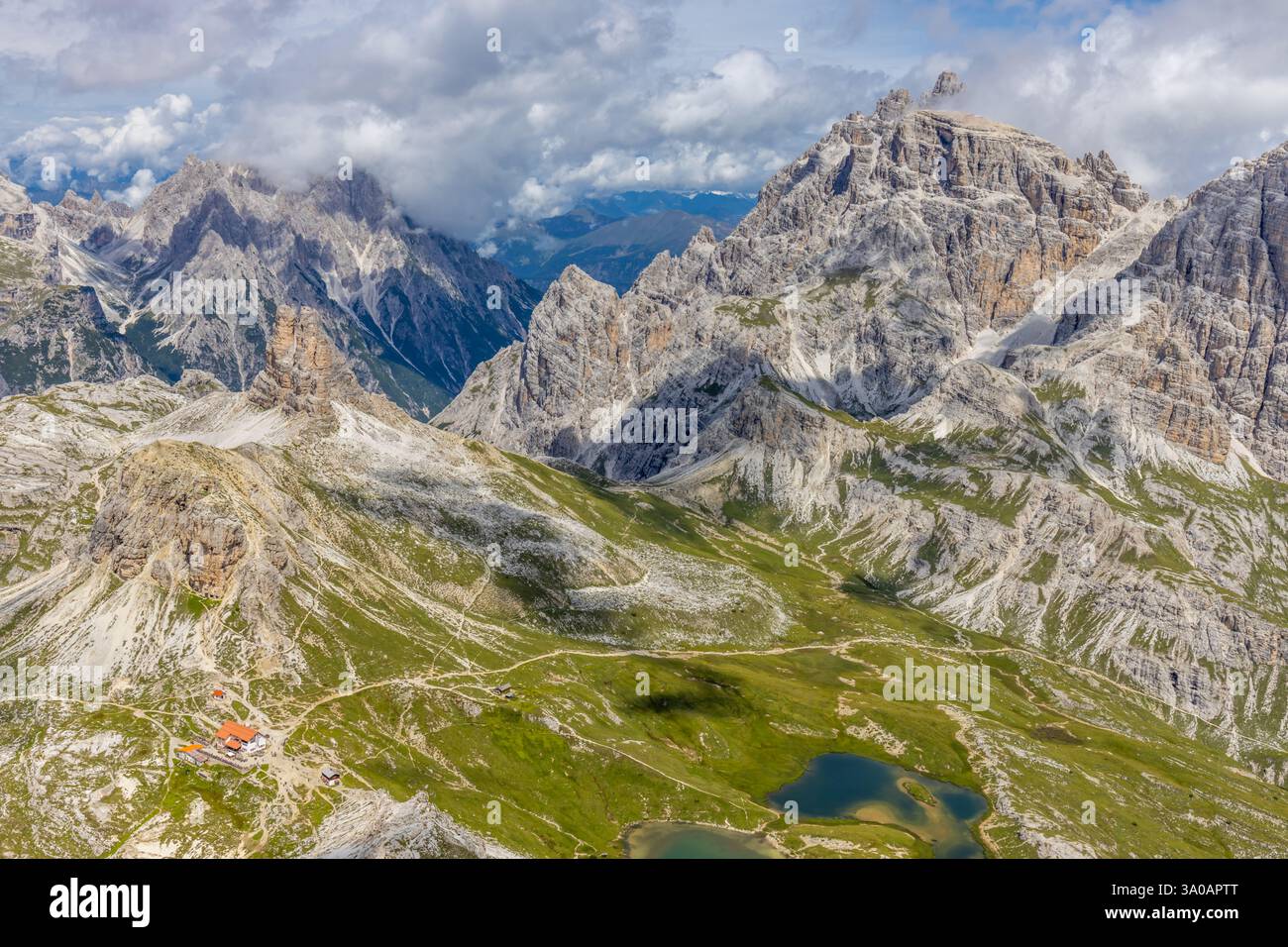 A mountain refuge at the base of rugged rock formations under a clear ...