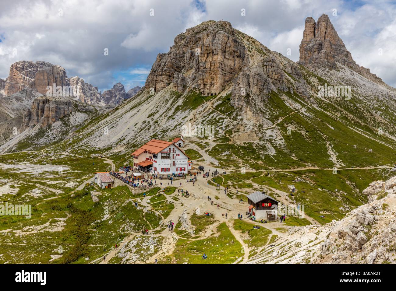 A mountain refuge at the base of rugged rock formations under a clear ...