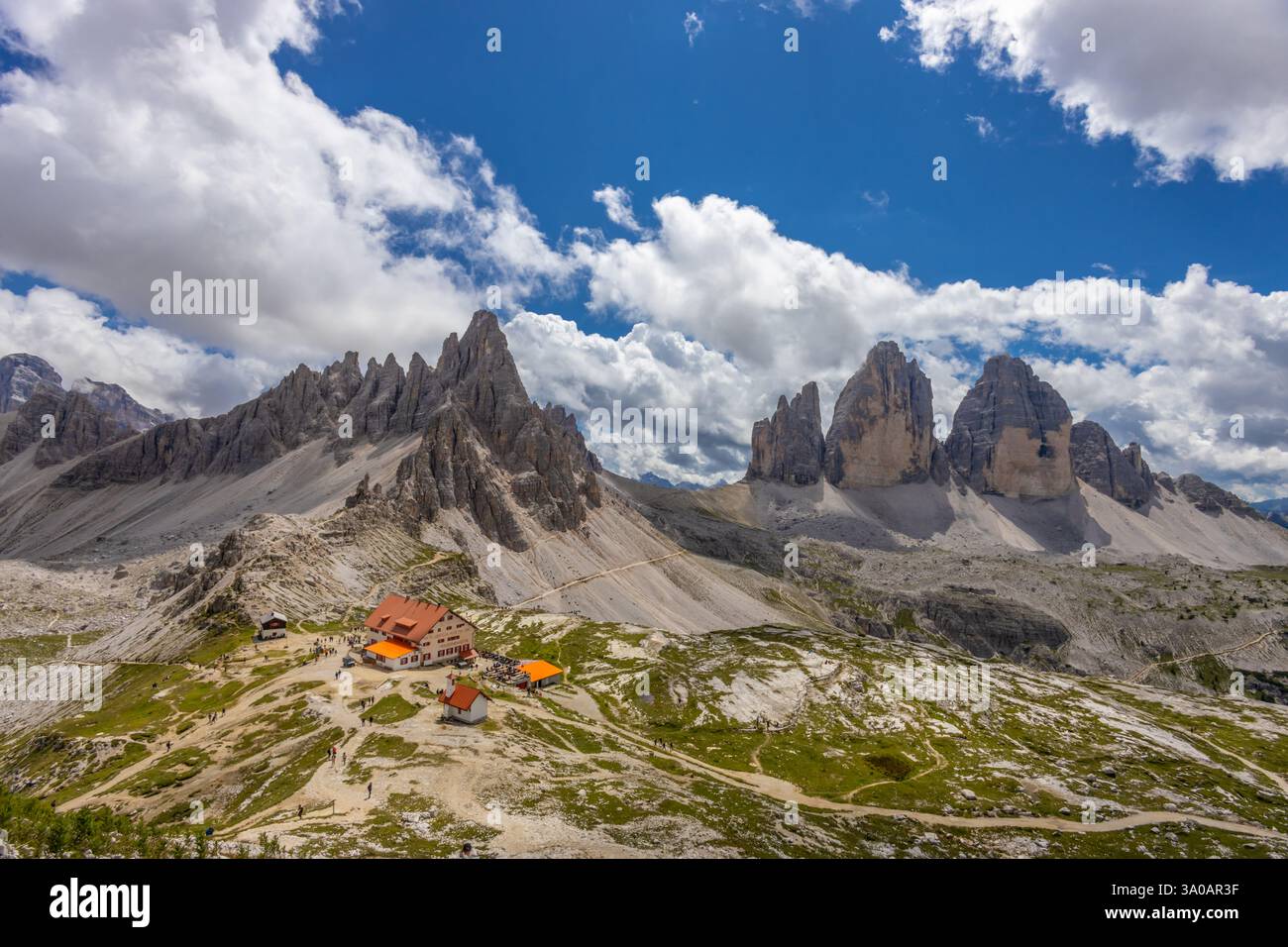 A mountain refuge at the base of rugged rock formations under a clear ...