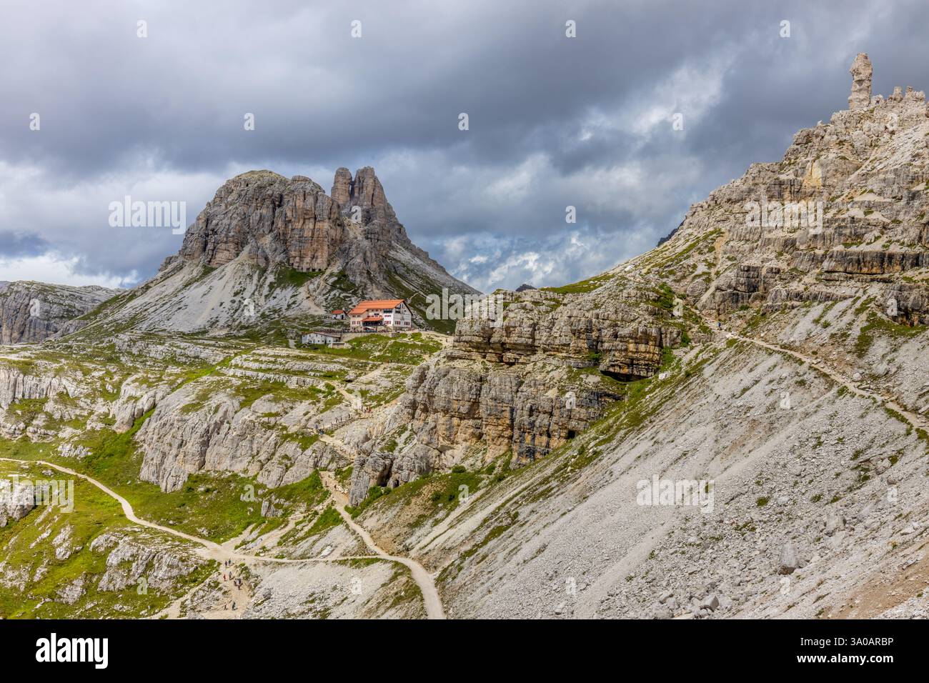 A mountain refuge at the base of rugged rock formations under a clear ...