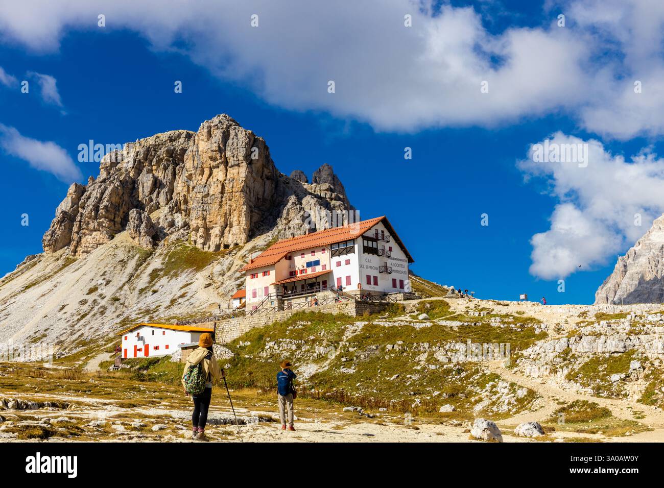 A mountain refuge at the base of rugged rock formations under a clear ...