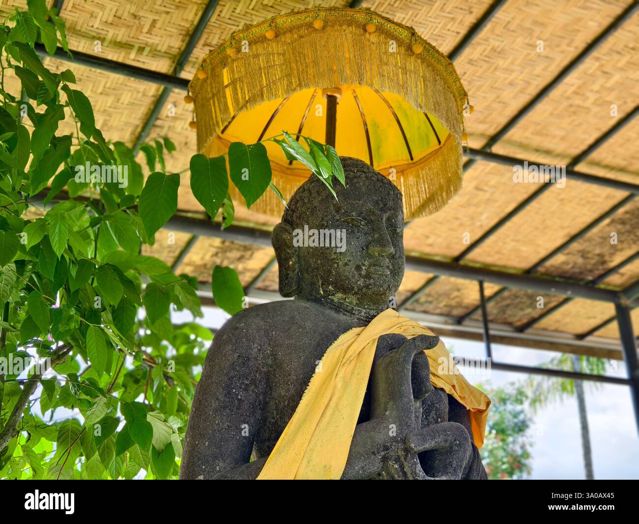 Tabanan, Bali, Indonesia - March 1, 2025 : A stone Balinese budha statue under a decorative ...