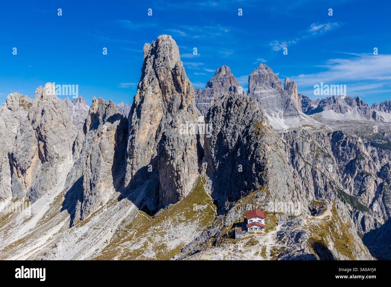 A mountain refuge at the base of rugged rock formations under a clear ...