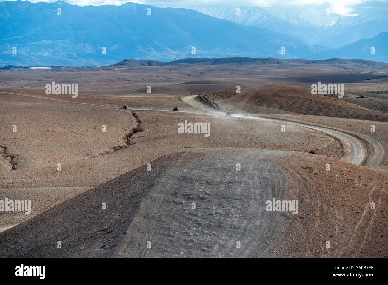 Winding dirt road cuts through the barren landscape of Agafay Desert in ...