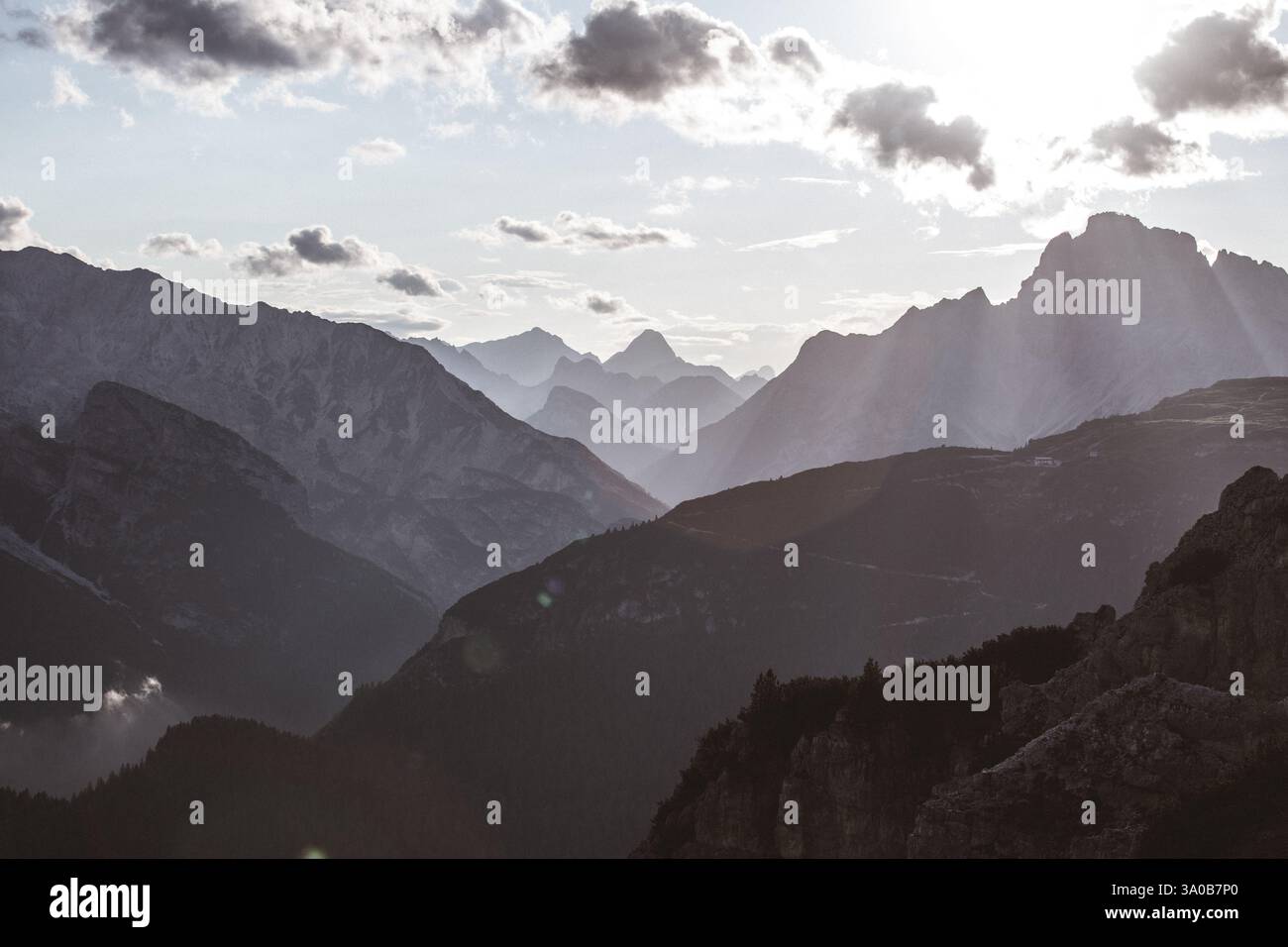 Majestic mountains stretch across the horizon in Europe, with sunlight breaking through clouds ...