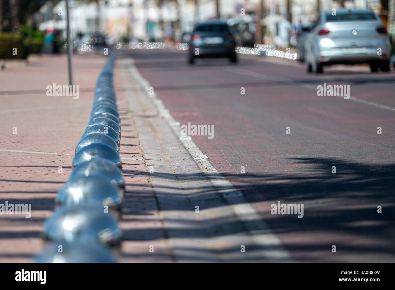 Cars drive along a clean road lined with decorative metal barriers in ...