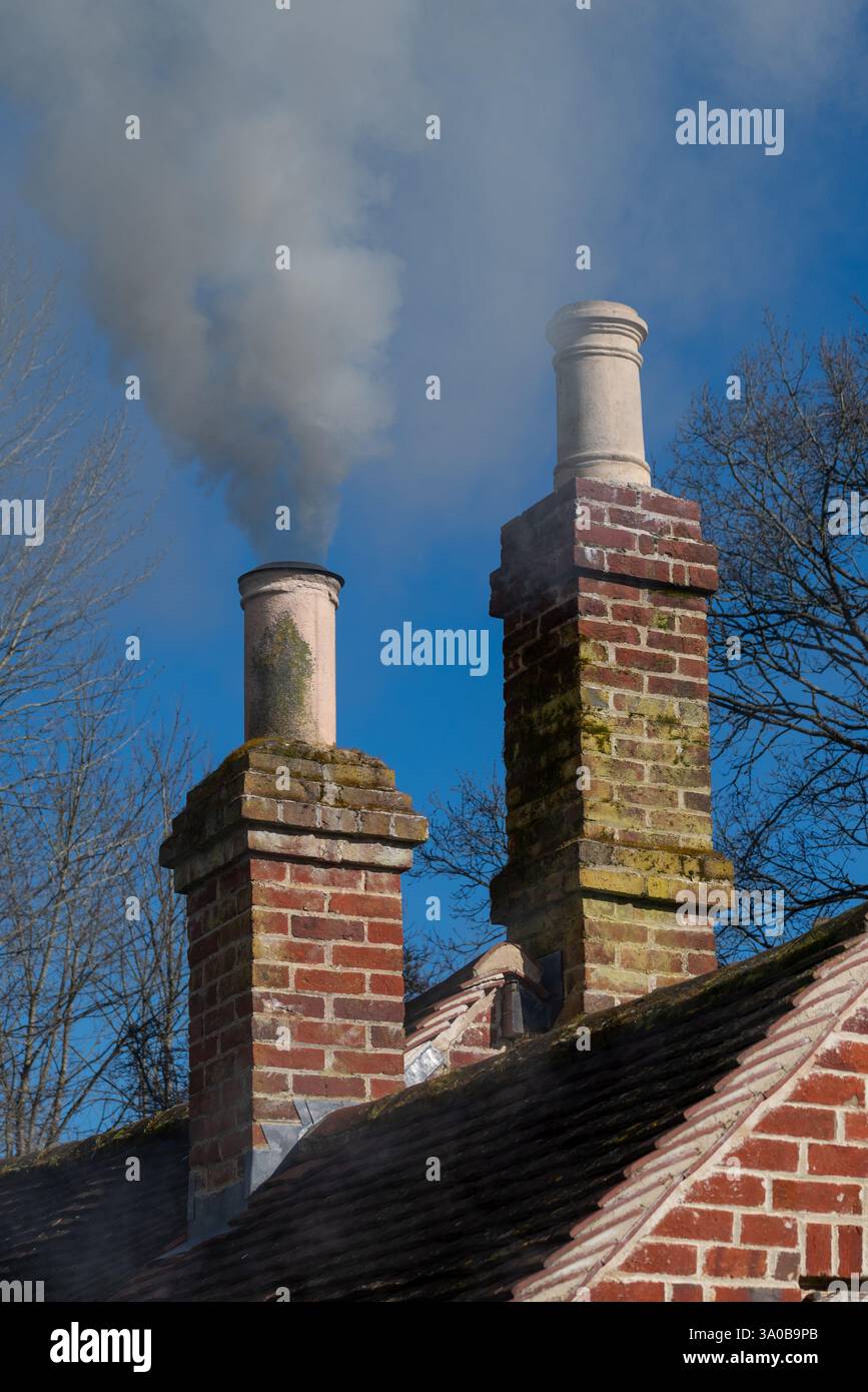 Old chimney puffing out smoke on a sunny day against a blue sky ...